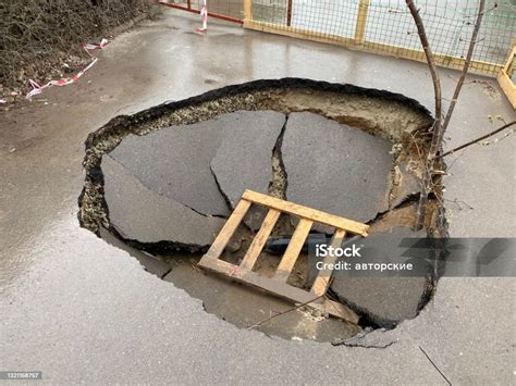 아스팔트 도로의 치명적인 파괴 캔버스의 깊은 구멍 울타리로 둘러싸인 큰 구덩이 고속도로 건설 기술과 보도의 가난한 건설 파괴된 도로 도로 구멍에 대한 스톡 사진 및 기타