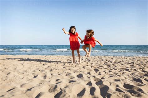 Zwei Kleine Schwestern Springen Zusammen Am Strand Lizenzfreies Stockfoto