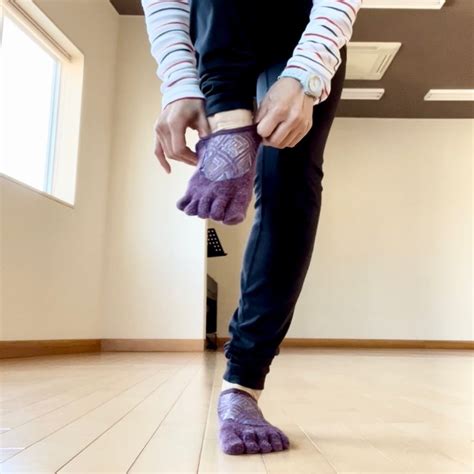 片脚立ちで五本指ソックスをはく ピラティスで カラダもココロも しなやかに