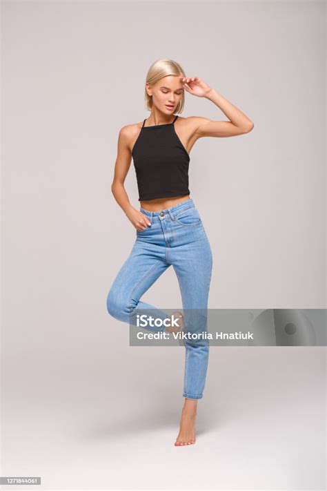 자유형 젊은 금발의 여자 청바지와 상단에 서 한 쪽 다리에 고립 된 흰색 전신 샷 터치 이마 우려 20 24세에 대한 스톡 사진 및 기타 이미지 Istock