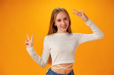 Teen Girl Makes Peace Or Victory Sign Over Yellow Background Stock