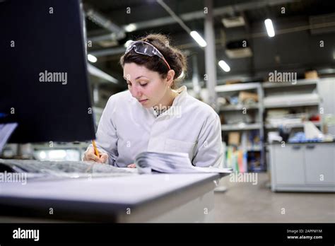 Serious Brunette Woman Lab Technician Sitting At Table With Computer And Carbon Mesh Blurred