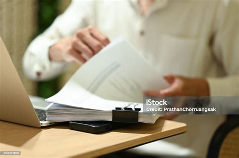 노트북 앞에 앉아서 나무 사무실 책상 위에서 서류를 작업하고 있는 정체불명의 사업가 30 34세에 대한 스톡 사진 및 기타
