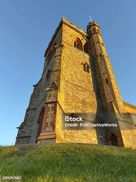 고딕 양식의 창문이 있는 인상적인 유서 깊은 석탑은 맑고 푸른 하늘을 배경으로 따뜻한 황금빛 햇살을 받고 있습니다 0명에 대한