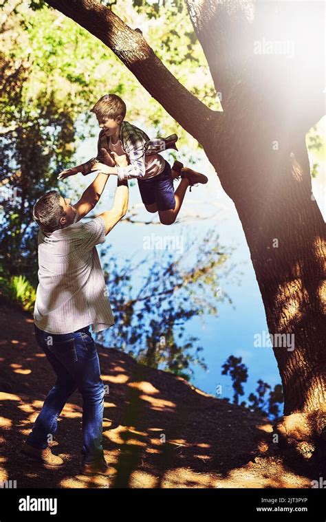 Higher Daddy A Father Playing A Game With His Young Son In The Woods