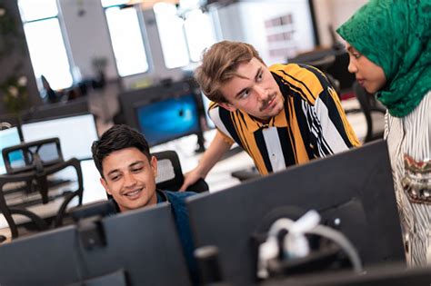 다민족 스타트업 비즈니스 팀 인 아라비아 여성이 노트북과 데스크톱 컴퓨터에서 작업하면서 현대 오픈 플랜 사무실 인테리어 브레인 스토밍에서 회의에 히잡을 착용하고 있습니다