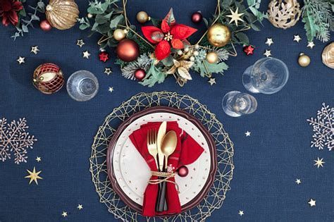 어두운 빨간색 흰색 접시 빨간 종이 반지와 Poinsettia 황금 기구와 크리스마스 테이블 설정 빨간색 녹색 및 황금 금박 장식 플랫 레이 고전적인 파란색 린넨 섬유