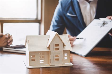 부동산 브로커 에이전트 제시 하 고 의사 결정 서명 보험 양식 계약 홈 모델에 대 한 고객에 게 상담 모기지 대출 제안 및 주택 보험에 관한 부동산에 대한 스톡 사진 및