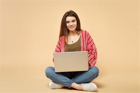 스튜디오에서 파스텔 베이 지 벽 배경에 고립 된 노트북 Pc 컴퓨터를 사용 하 여 앉아 캐주얼 옷에 흥분 젊은 여자의 초상화 사람들은 진심으로 감정 라이프 스타일 개념입니다