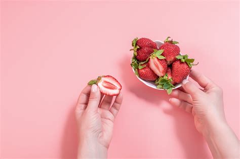 분홍색 배경에 흰색 그릇에 신선한 껍질을 벗긴 딸기를 클로즈업 한 여성의 손이 그릇에서 딸기를 가져간다 가득 찬에 대한 스톡 사진 및 기타 이미지 Istock