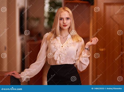 Young Attractive Blonde In A White Blouse Posing At Home With Her Arms