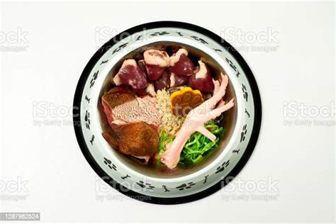 흰색 배경에 그릇에 건강한 생 신선한 개 음식 생 쇠고기 고기와 오프탈 닭 발 오리 마음 녹색 야채와 음식 보충제 상단 보기
