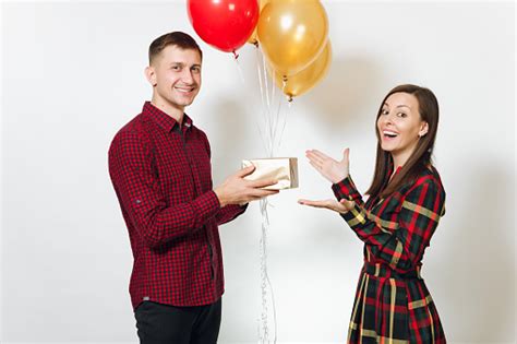 아름 다운 젊은 행복 미소 커플 사랑에 여자와 남자와 황금 선물 상자를 들고 제시 하 고 빨강 노랑 흰색 바탕에 생일 축 하