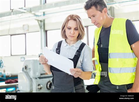 Male And Female Manual Workers Examining Paper In Industry Stock Photo Alamy