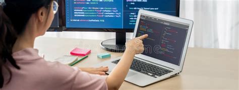 Female Developer Coding On Laptop While Computer Display Program