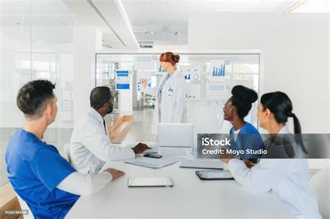 의료 프리젠 테이션 지도자를 듣는 의사 및 간호사는 병원 회의실에서 통계 그래프 및 인포 그래픽 연구에 대해 이야기합니다 의료
