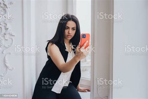 화가 난 아프리카 계 미국인 젊은 여성은 집에서 좌절 한 얼굴 표정으로 창턱에 앉아 휴대 전화로 화상 통화 중에 나쁜 소식을 받았습니다 사무실에서 걱정하는 브라질 소녀가