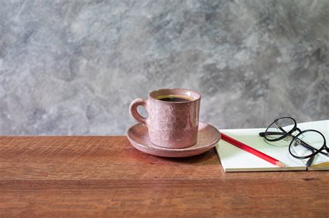 나무 테이블에 오래 된 컵 커피 파스텔 핑크의 클로즈업 빈 열린 소책자 안경 빨간 연필과 쓰기 노트북 창에서 아침 빛 교육 개념