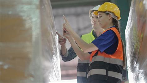 단단한 모자와 안전 조끼를 착용하고 제조 보관소를 검사하는 창고 근로자 팀 직원은 시스템을로드하고 수령 및 분배하고 유통