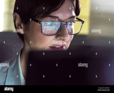 a focused individual wearing glasses with computer code reflection in