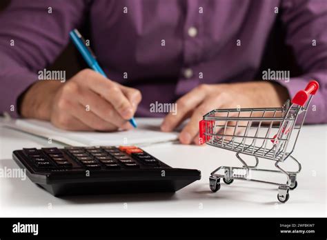 Man Calculates The Budget Shopping Cart A On Table With Calculator And Paper Budget Of Poor