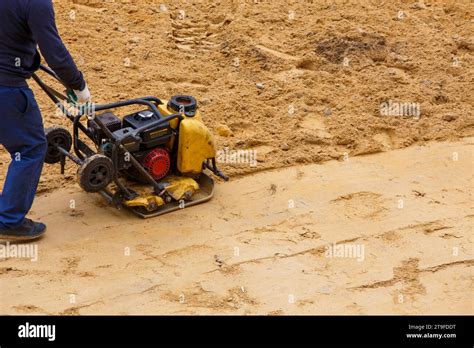Worker Using Vibratory Plate Compactor For Compaction Sand During Path