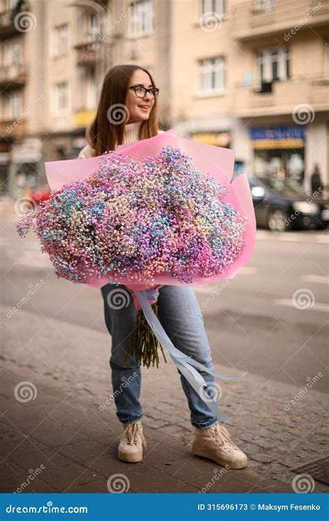 Smiling Girl With Glasses In Black Frame Jeans And Sports Shoes Stands On A Street Stock Image