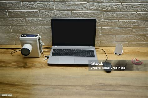 복사 광고 공간이있는 빈 모니터 화면이있는 노트북 치과 의사의 사무실의 나무 테이블에 파노라마 엑스레이와 턱의 치과 느낌을 만드는 휴대용 치과 X 선 기계 0명에 대한 스톡