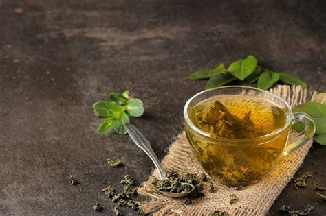 녹차 어두운 배경에 민트와 마른 찻잎이 있는 컵에 뜨거운 차 박하 요리에 대한 스톡 사진 및 기타 이미지 박하 요리 스티핑