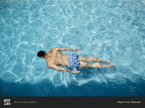 Back View Of Man Floating In Swimming Pool Stock Photo OFFSET
