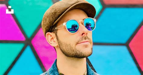 모자와 선글라스를 쓴 남자가 화려한 벽 앞에 서 있다 사진 Unsplash의 무료 소매 이미지