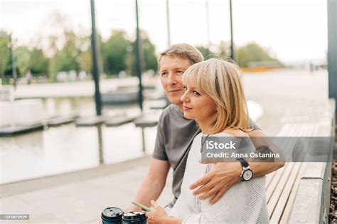 도시 거리 공원에서 야외 벤치에 앉아 사랑에 성인 성숙한 행복한 부부 금발의 백인 남자와 여자는 함께 시간을 보내고 커피를 마시는 선임 아내와 남편 산책 외부 2명에 대한