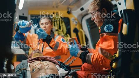 여성과 남성 Ems 구급대원은 의료 병원으로 가는 길에 부상당한 환자에게 의료 지원을 제공합니다 구급차에 비 침습적 환기 마스크를 착용 응급 치료 조수 35 39세에 대한