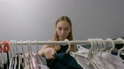 Blondy Cute Teen Girl Is Choosing Clothes Hanging On The Racks In Her Wardrobe At Home Fashion