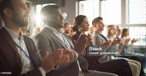 기술 회의에서 붐비는 강당에 앉아 있는 아프리카계 미국인 남자 기조연설을 듣고 있는 흑인 사업가 혁신적인 기술 발표를 지켜보고 청중과 박수를 치는 전문가 기조연설에 대한
