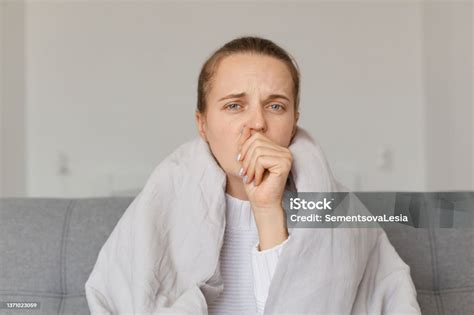 담요 아래에 두통이 있는 아픈 여성의 초상화 기침 입 가까이에 손을 잡고 슬픈 표정을 지으며 인플루엔자 증상을 보입니다 감기와 독감에 대한 스톡 사진 및 기타 이미지