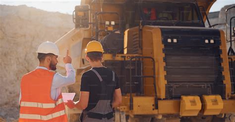 운반 트럭 근처에 서서 문서에 대해 이야기합니다 제복을 입은 두 남자가 채석장에서 함께 일하고 있습니다 사진 Unsplash의 굴 착 기 이미지