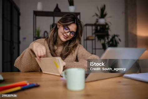 아늑하고 잘 꾸며진 홈 오피스의 책상에서 일하면서 책을 읽고 있는 여성 가정 생활에 대한 스톡 사진 및 기타 이미지 가정