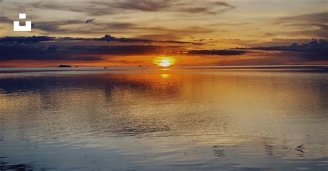 태양은 하늘에 구름과 함께 물 위에지고있다 사진 Unsplash의 무료 갈색 이미지