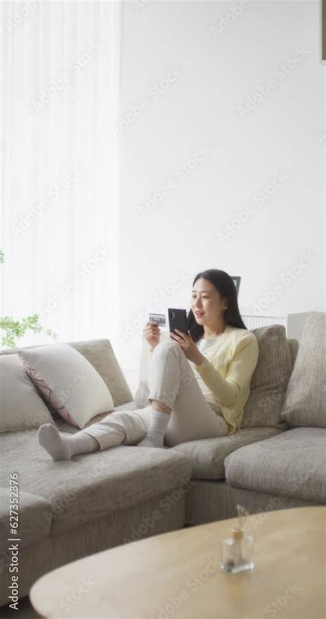세로 화면 거실에서 스마트폰과 신용카드를 들고 모바일 쇼핑을 하는 여성 Stock Video Adobe Stock
