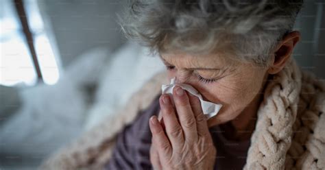 집에서 침대에 누워 재채기를 하고 코를 푸는 아픈 선배 여성 사진 Unsplash의 옛 이미지