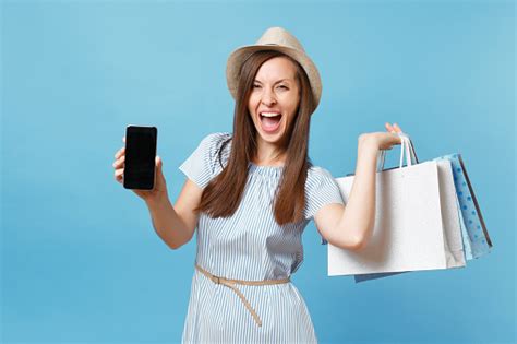 여름에 여자의 초상화 드레스 밀 짚 모자 블루 파스텔 배경에서 분리 하는 빈 화면으로 쇼핑 모바일 핸드폰 후 구입 패키지 가방을 들고 광고에 대 한 공간을 복사 합니다