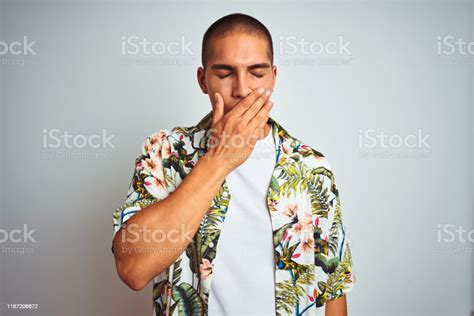 휴일에 젊은 잘 생긴 남자는 흰색 배경에 하와이 셔츠를 입고 지루한 하품 손으로 입을 덮는 피곤 불안과 졸음 가리기에 대한 스톡 사진 및 기타 이미지 Istock
