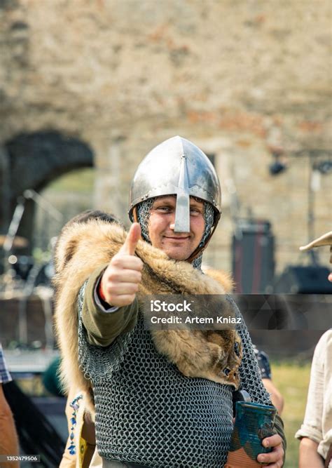 헬멧을 들고 철갑옷을 입은 웃는 기사 남성 초상화가 손으로 엄지손가락을 치켜들고 역사적인 재건과 코스프레 페스티벌 야외 수직 사진 기사 사람의 역할에 대한 스톡 사진 및