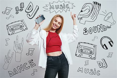 음악을 위한 시간 음악 테마 기념일 로고와 회색 배경에 서 서 그녀의 스마트 폰과 음악을 듣고 춤과 웃는 얼굴에 젊은 여자의 초상화를 닫습니다 Dj에 대한 스톡 사진 및
