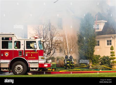 Two Firefighters Holding Hose Spraying Water At House Fire At 84