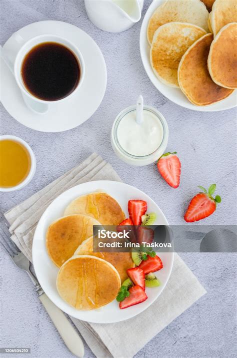 꿀 사워 크림 신선한 딸기와 커피 한 잔과 흰색 접시에 키위와 케피어에 전통적인 러시아 팬케이크 건강한 아침 식사 러시아어 Maslenitsa입니다 수직 방향 맨 위 보기