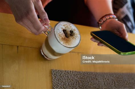 아침 카푸치노의 흰색 컵을 들고 흰색 세련된 드레스를 입고 빈티지 하트 선글라스를 테이블에 올려 놓고 혼자 시간을 보내는 여성의 패션 이미지를 닫습니다 인스 타 그램 색상