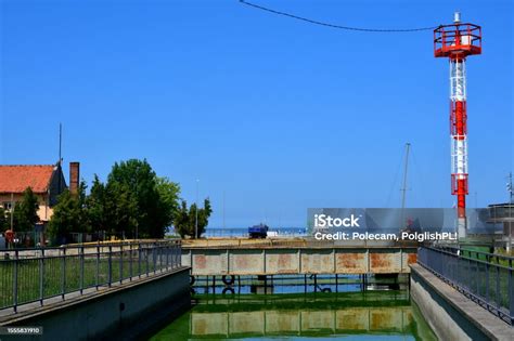 폴란드에서 볼 수 있는 금속으로 만든 붉은 색과 흰색 전망대로 둘러싸인 작은 개울과 광활한 바다 또는 바다를 연결하는 오래된 녹슨 금속 수문의 모습 0명에 대한 스톡 사진