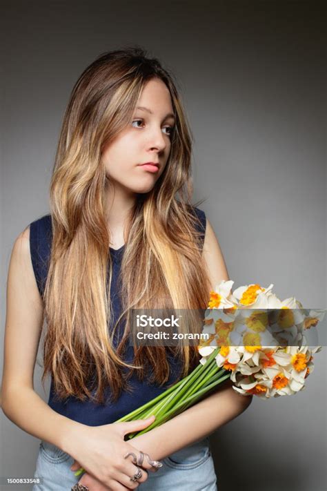 길고 자연스러운 금발 머리를 가진 십대 소녀는 시선을 돌리고 수선화를 들고 있다 14 15 살에 대한 스톡 사진 및 기타 이미지 14 15 살 Z세대 갈색 눈